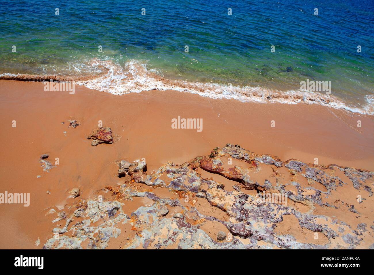 ocean waves and sandy beach with rocks Stock Photo - Alamy