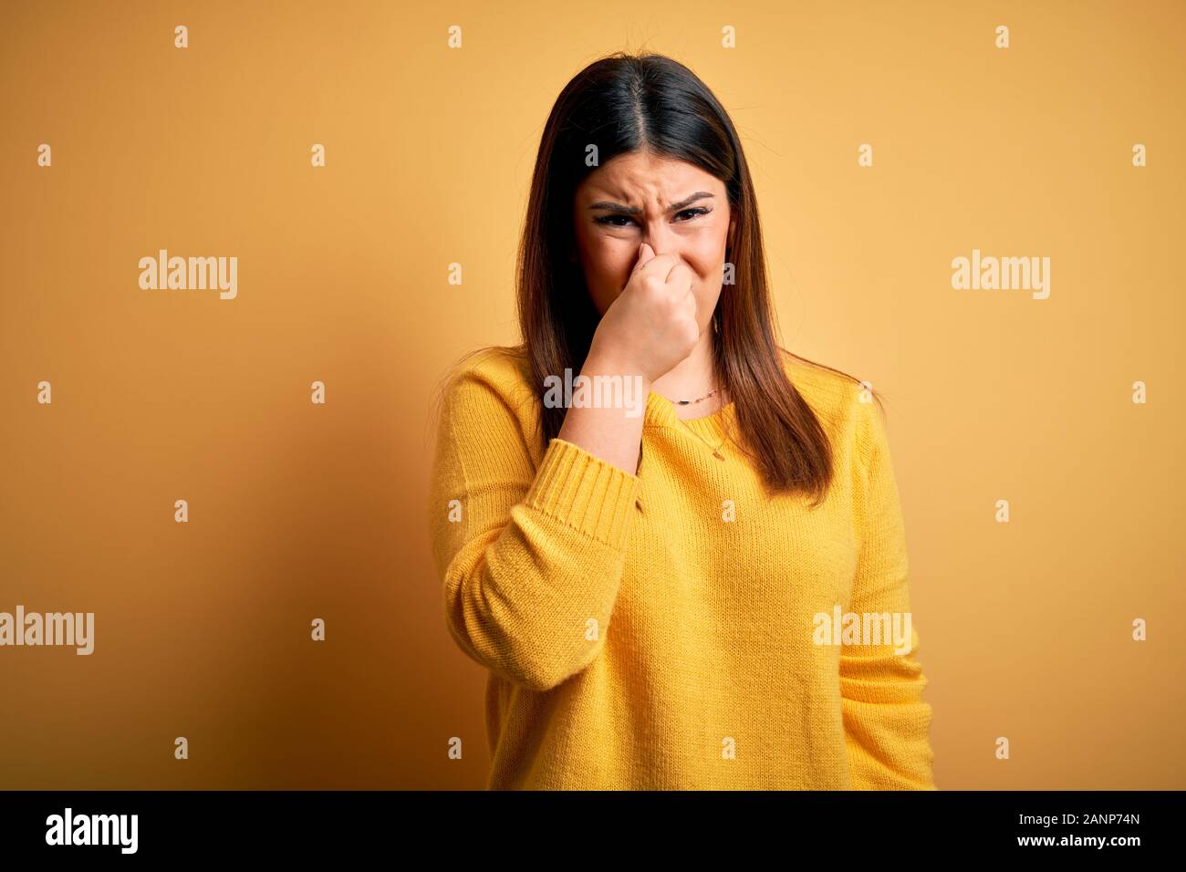 Young beautiful woman wearing casual sweater over yellow isolated ...
