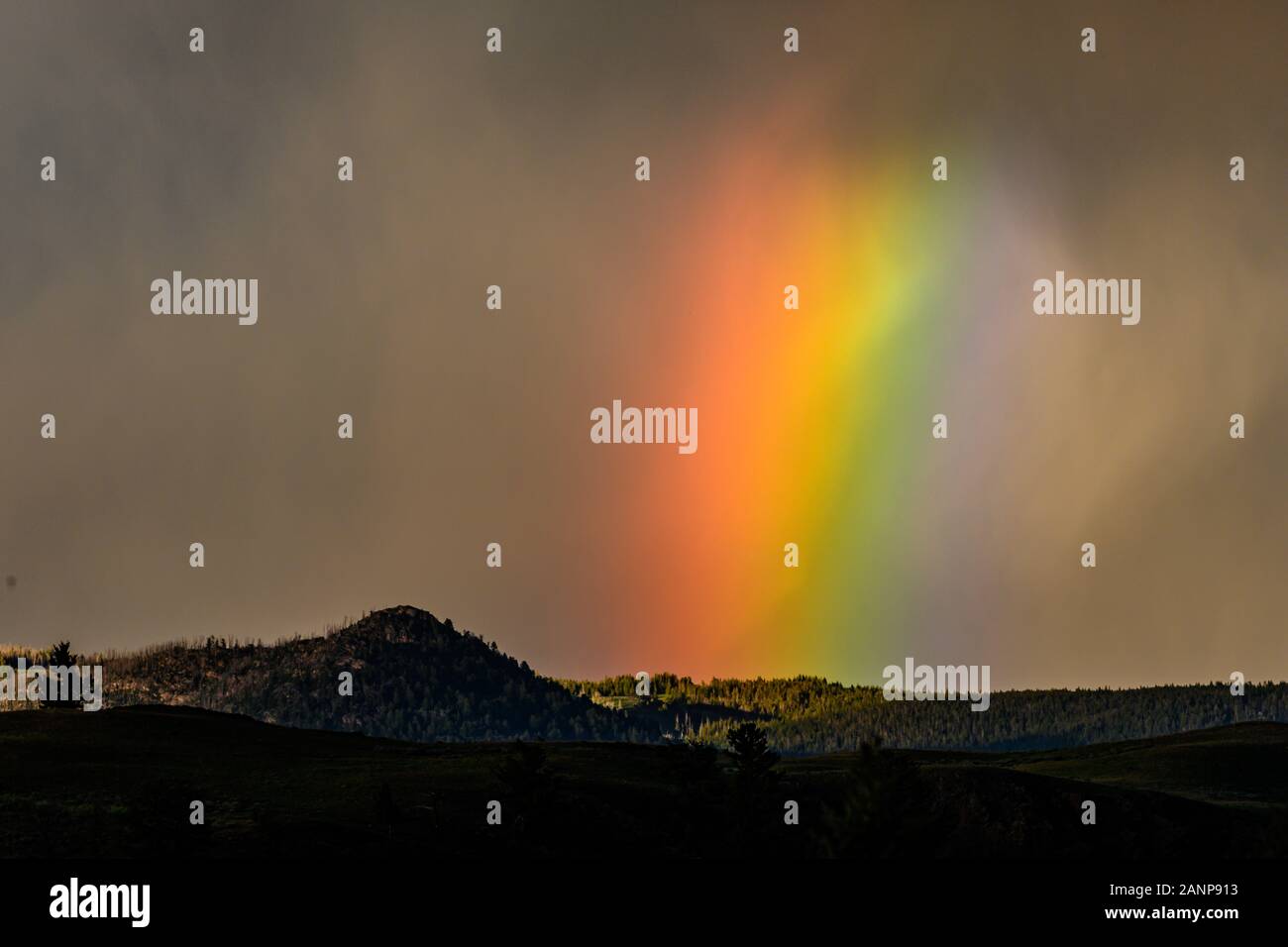 Wide Rainbow Glows Through Thick Storm Cloud over mountains Stock Photo ...