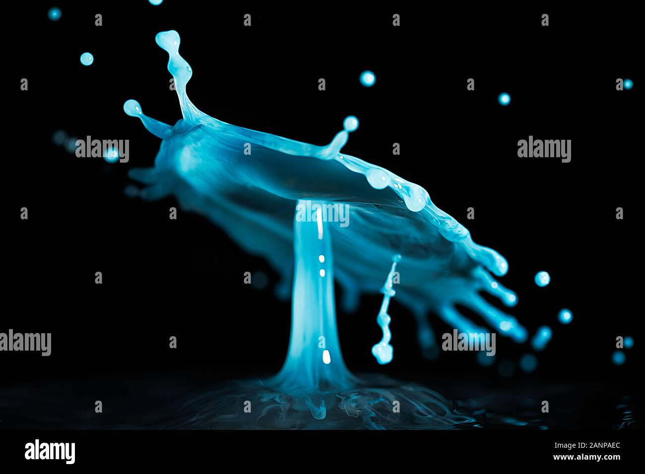 Baby blue colored milk splashes into water and is frozen in space with ...