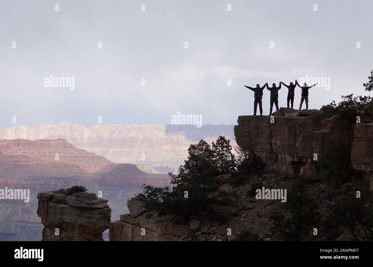 Four people standing at a cliff Stock Photo - Alamy