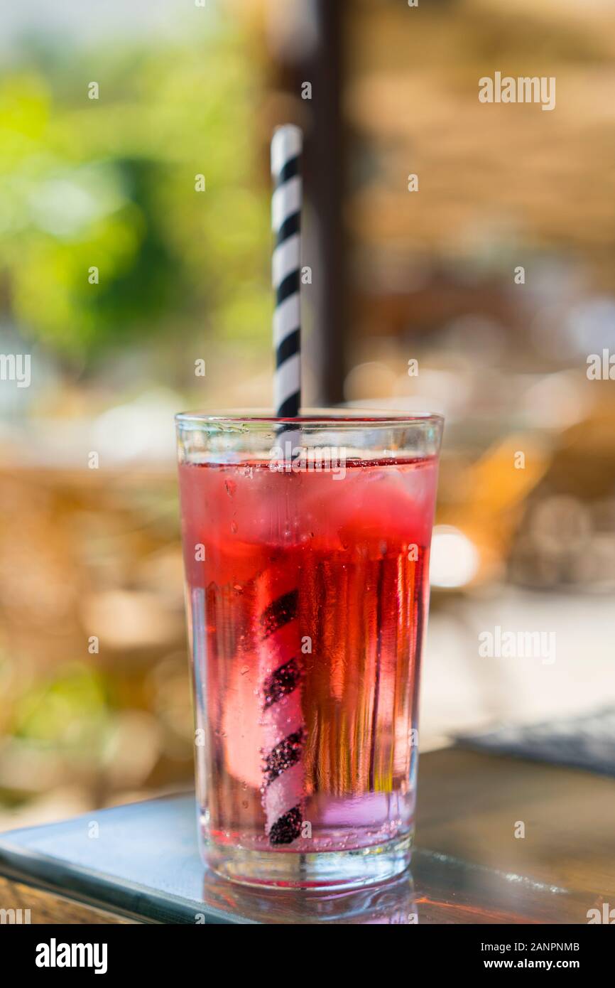 Red cocktail with ice with a straw on a on bar background. vertical photo Stock Photo - Alamy