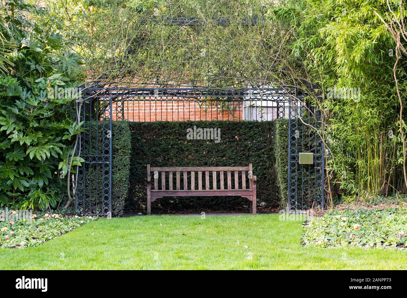 Wooden garden bench under a metal trellis frame Stock Photo - Alamy