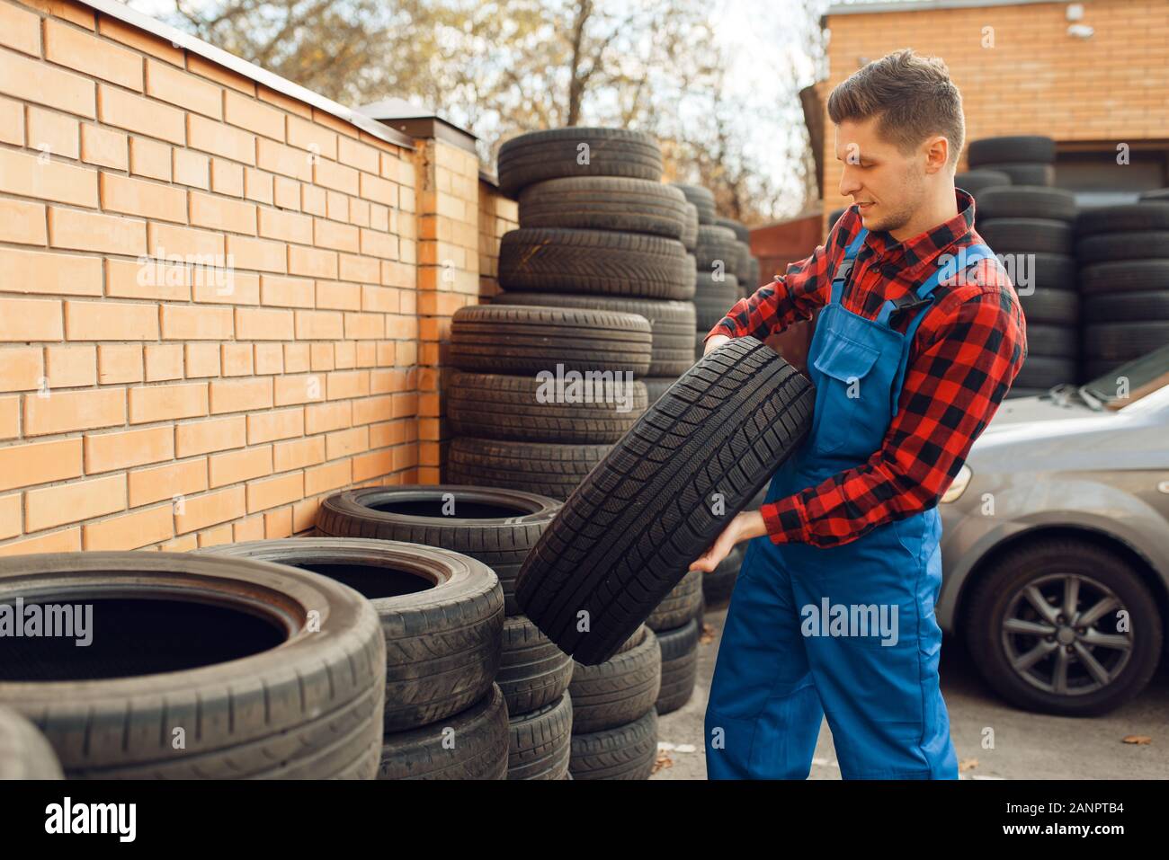 Male worker at the stack of tyres, tire service Stock Photo - Alamy