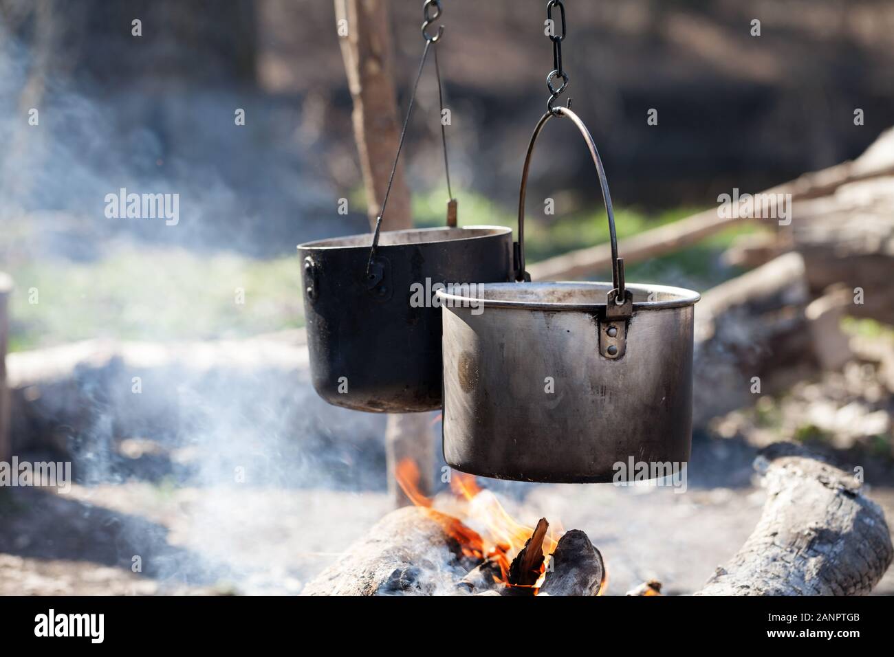 Cooking in two sooty old cauldrons on bonfire with smoke at forest in ...