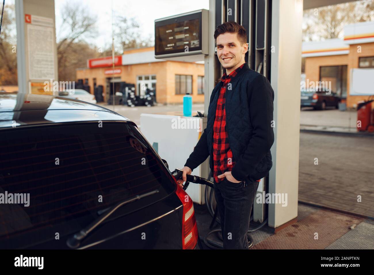 Man with gun fuels vehicle on gas station Stock Photo - Alamy