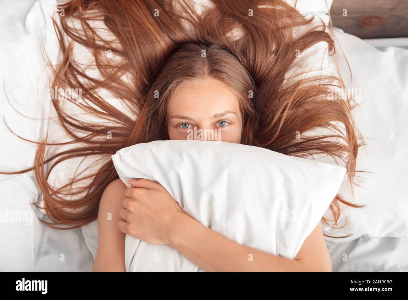 Morning At Home Woman Lying On Bed Hugging Pillow Smiling Playful To