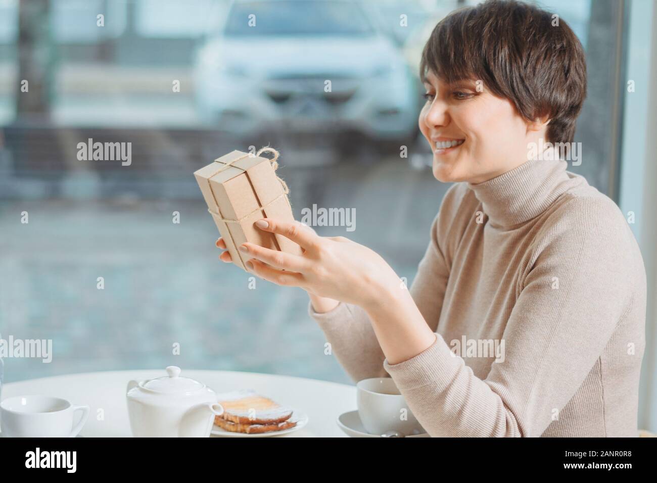 Young woman is opening a gift with a red ribbon hi-res stock ...