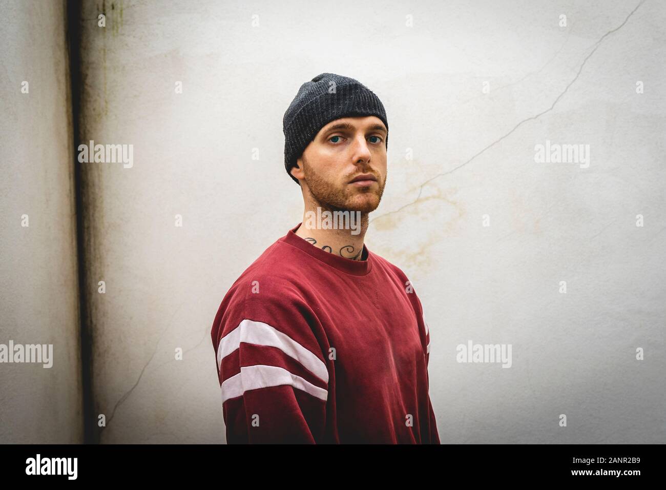 portrait of young rapper posing in front of a white wall in the suburbs ...