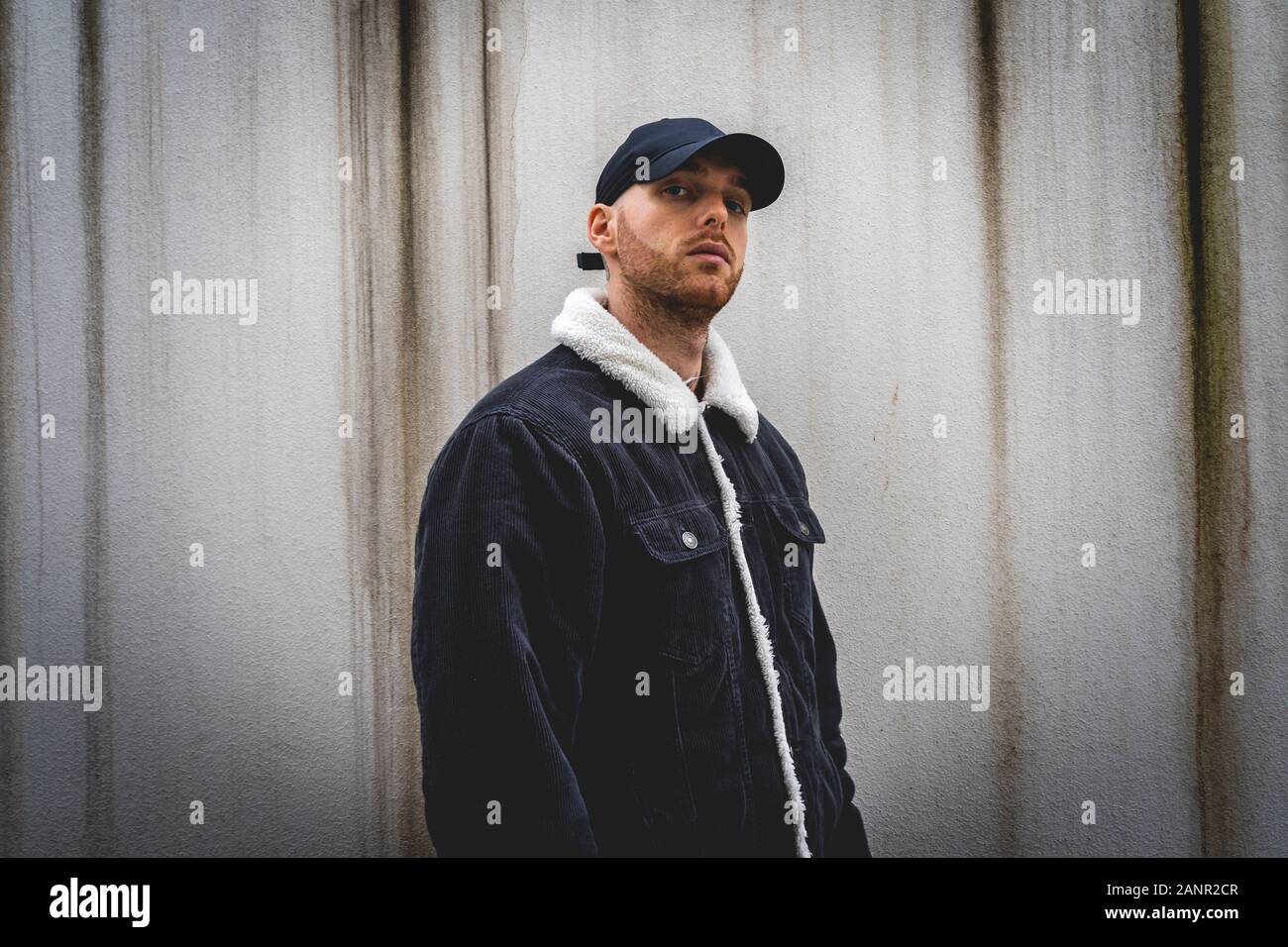 portrait of young rapper posing in front of a white wall in the suburbs ...