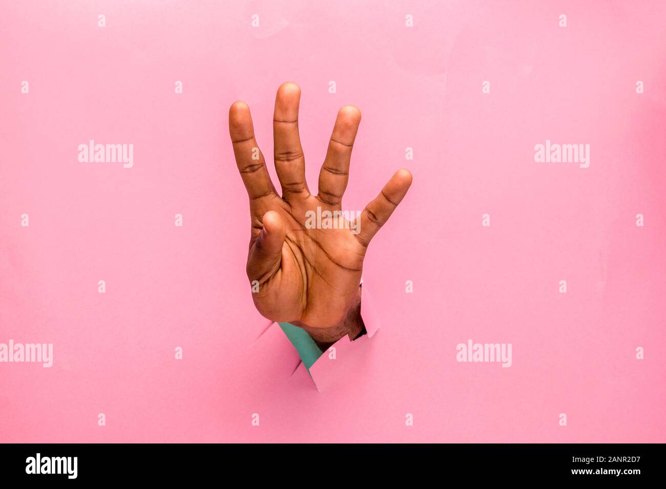 black person hand through a hole in a cardboard indicating number four ...