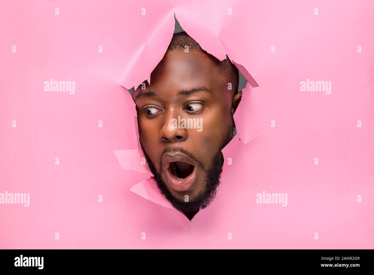 handsome young black man with head through a cardboard paper surprised ...