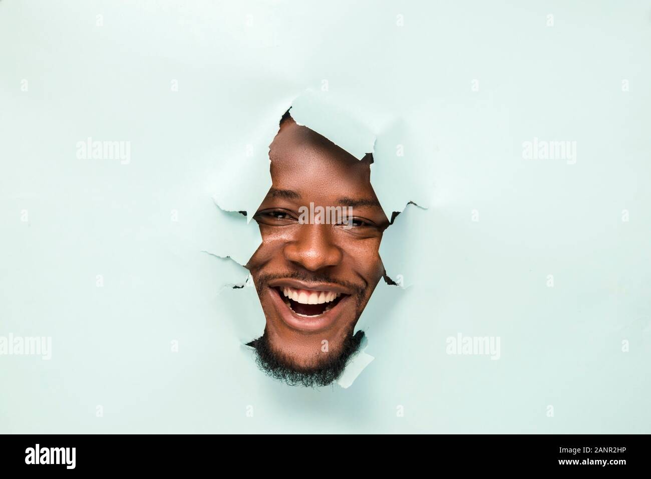 handsome young black man with head through a cardboard paper smiling ...