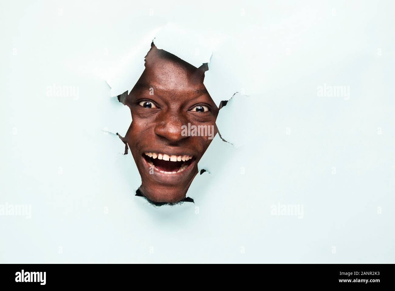 handsome young black man with head through a cardboard paper looking ...
