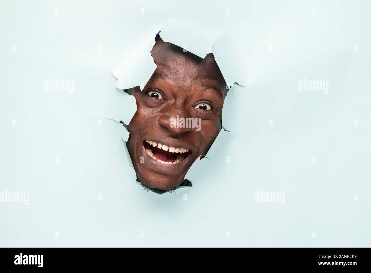 handsome young black man with head through a cardboard paper looking ...