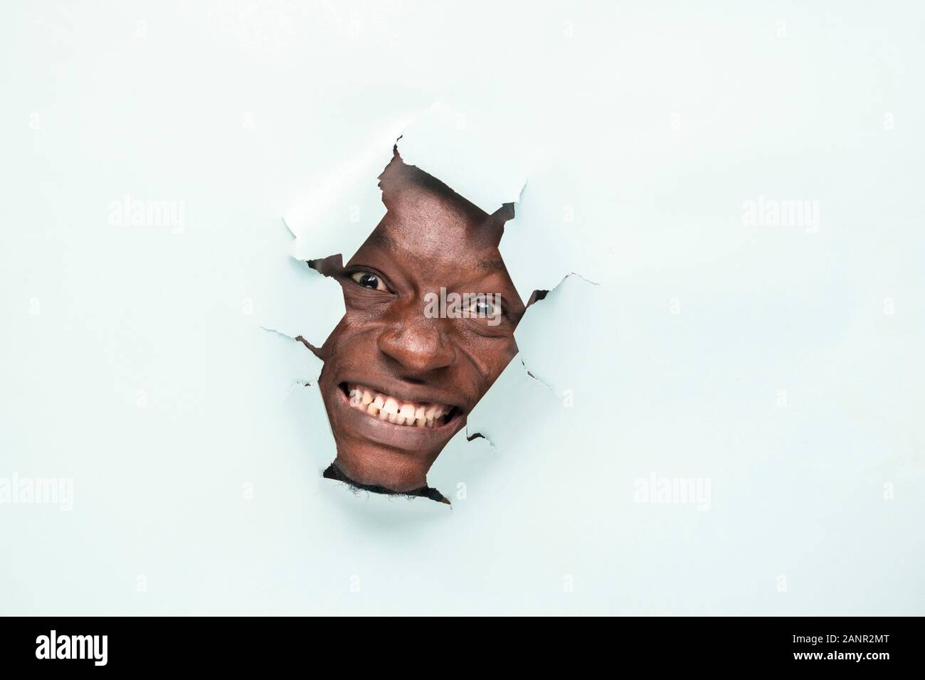 handsome young black man with head through a cardboard paper feeling ...