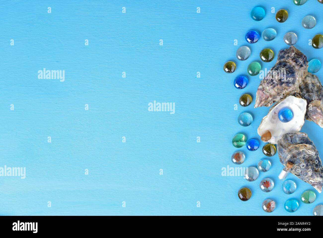 oyster shells and multi color glass stones on a blue background.copy ...