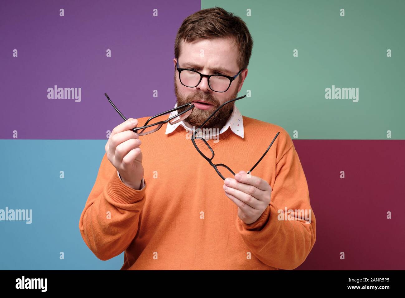 Bearded man in bewilderment and stupor, he selects and compares glasses ...