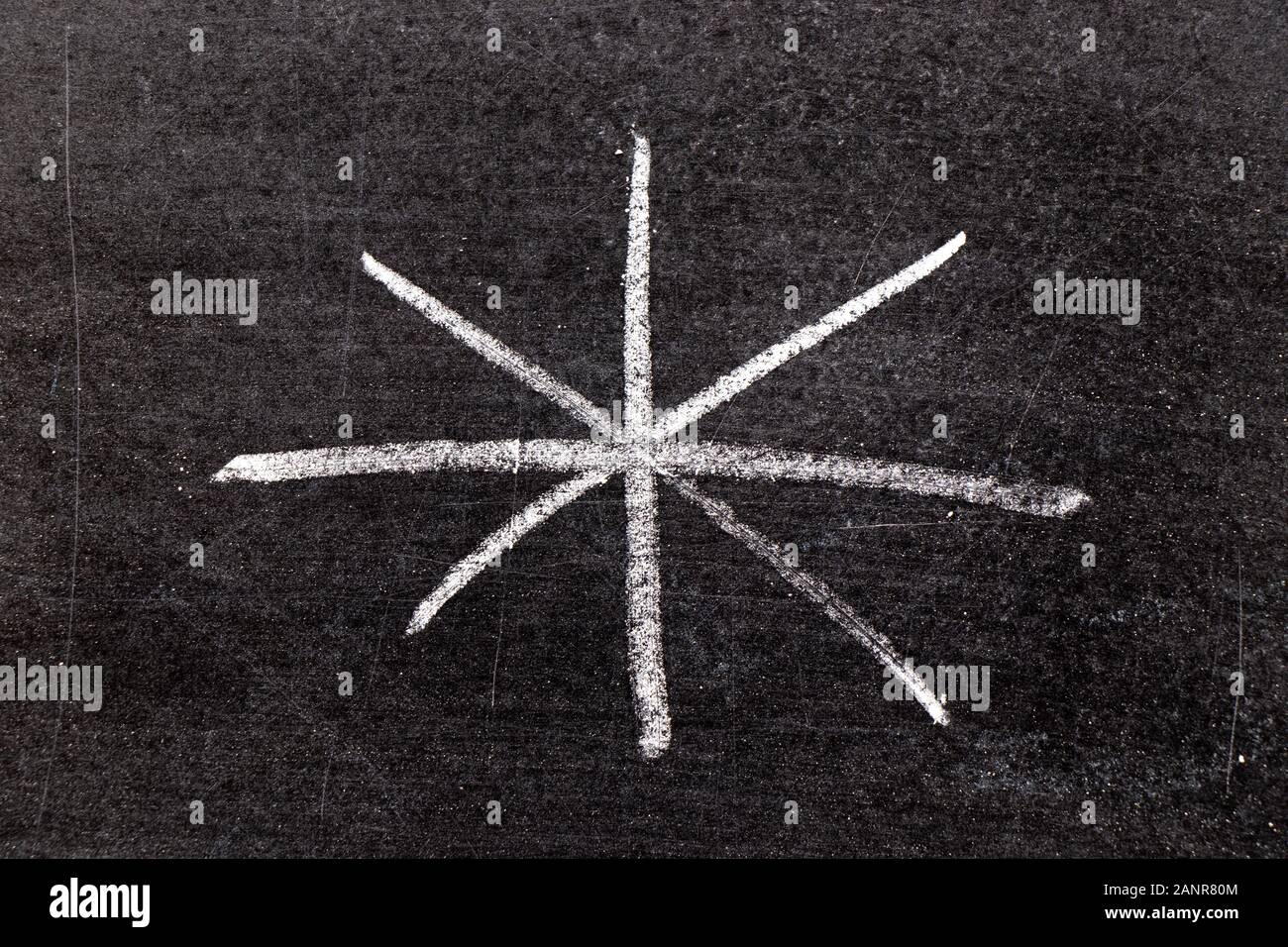 White chalk hand drawing in asterisk shape on black board background ...