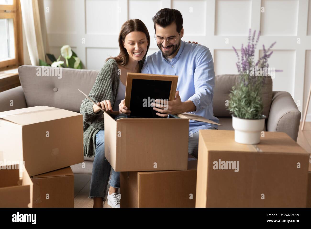 Happy couple unpack boxes settling at new home Stock Photo - Alamy