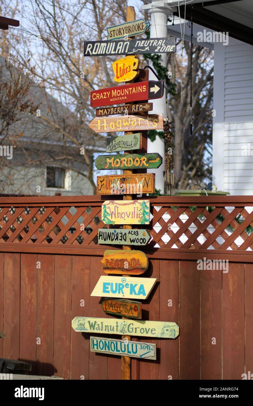 Decorative sign post with multiple destinations, some fictional such as ...