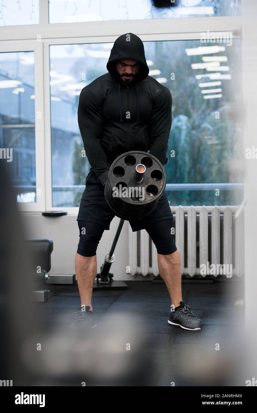 physical development of young man pulling heavy weight barbell in sport ...