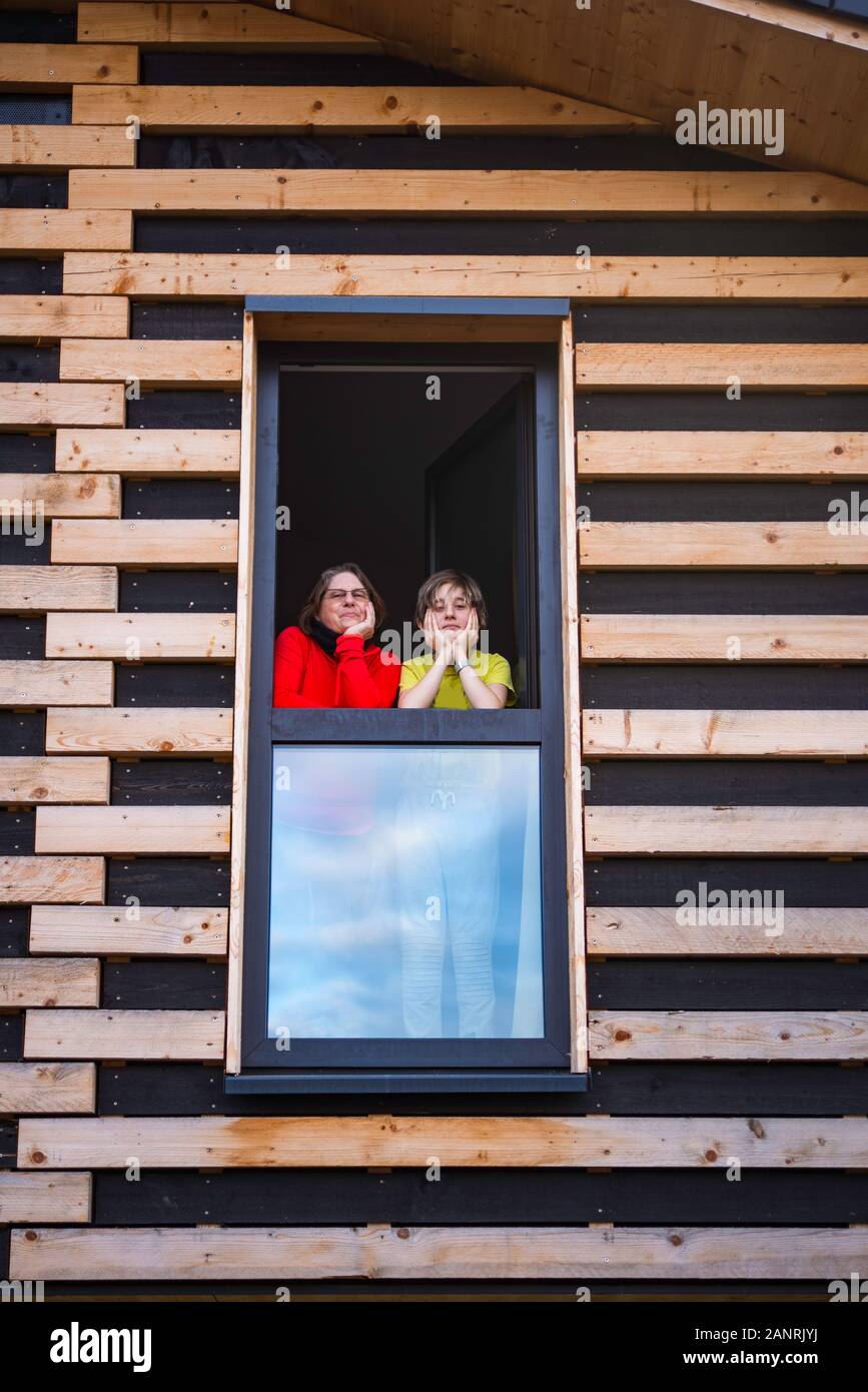 A woman and her son look down smiling from a window Stock Photo - Alamy