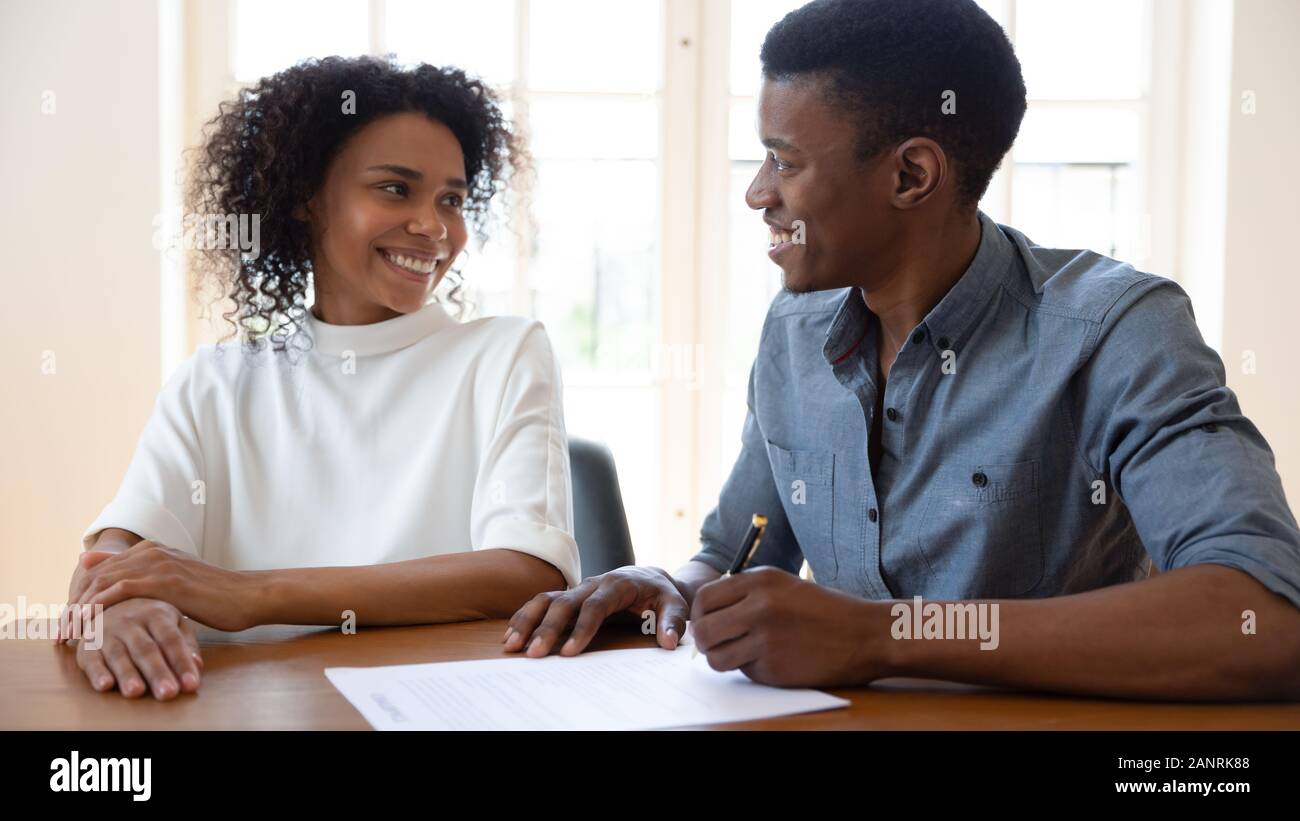 Happy African American couple making deal, signing contract in office ...