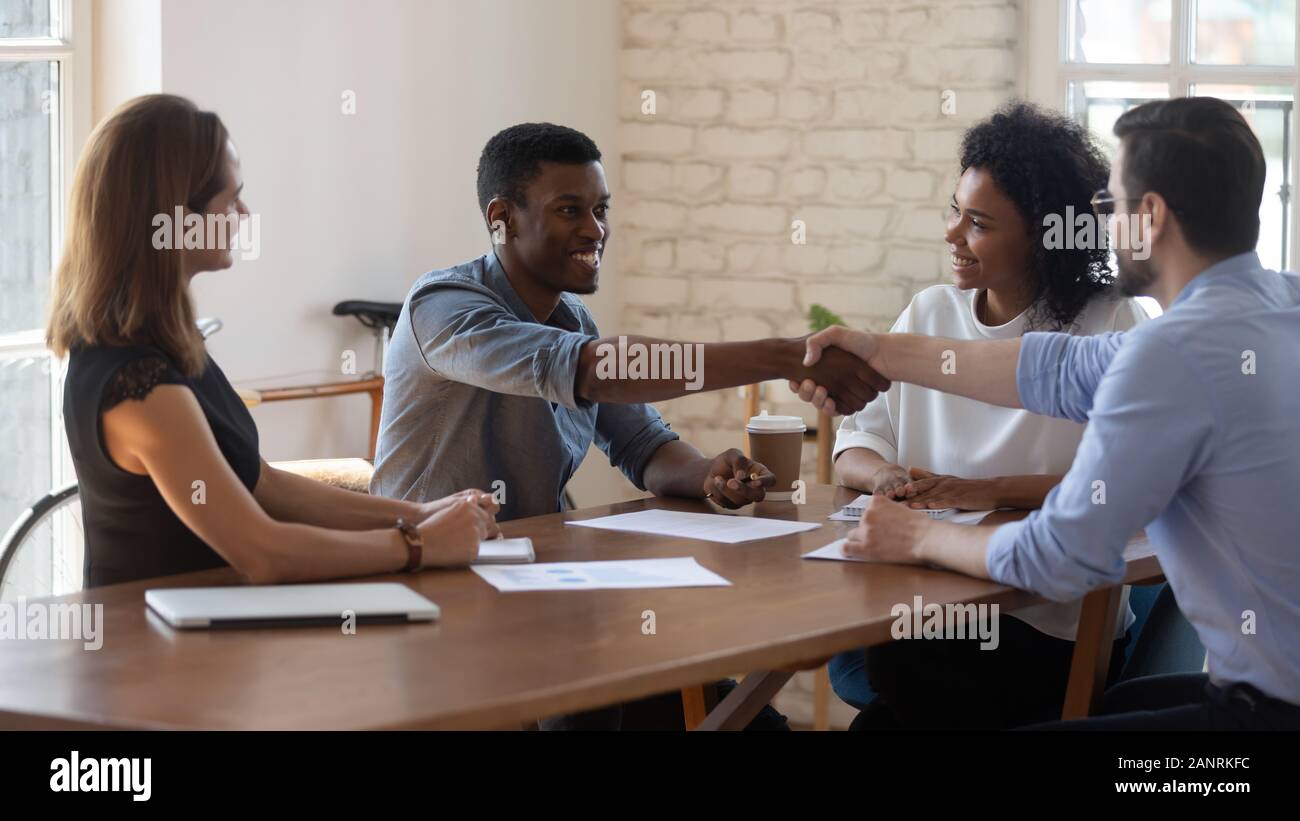 Happy diverse business partners shaking hands after successful ...