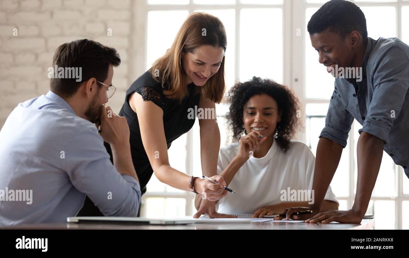 Happy diverse colleagues working on project documents together Stock ...