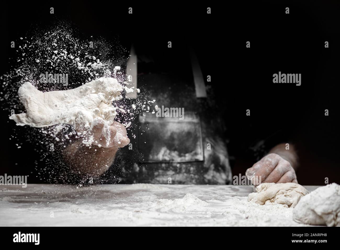 White powdery flour spraying into air while man hand baker cook on ...