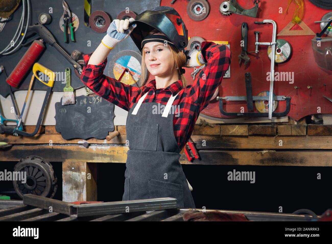 Beautiful girl engineer in mask welder is preparing for industrial work ...
