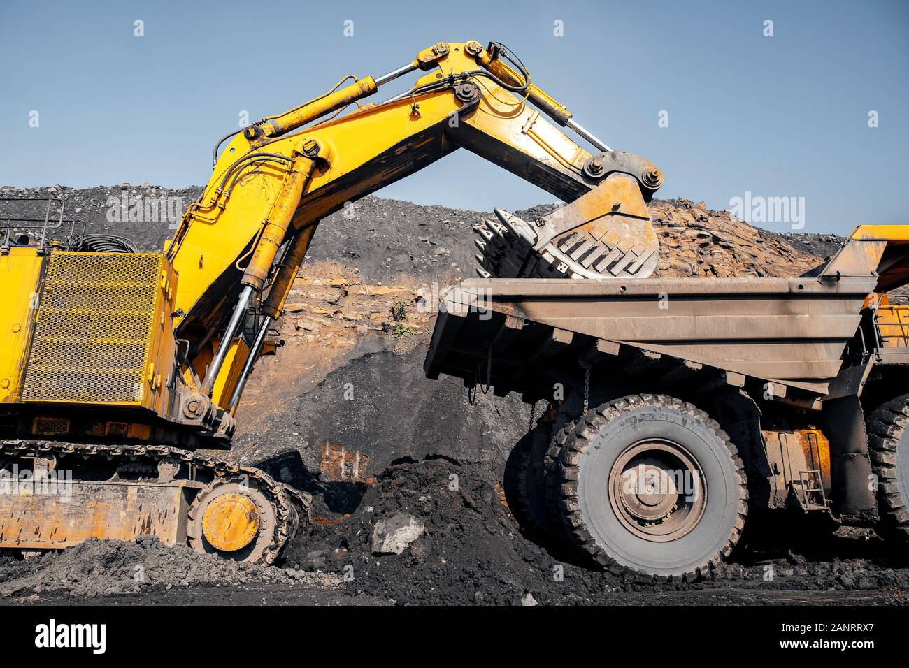 Open pit mine industry, excavator loading coal on big yellow mining ...