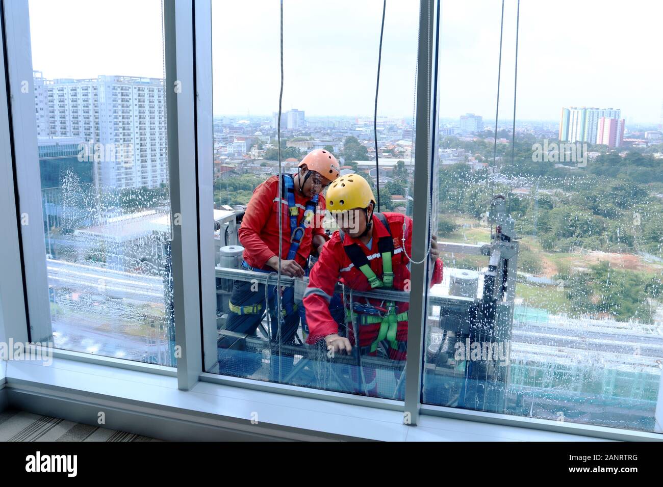 two workers cleaning windows service in high rise building in Jakarta ...