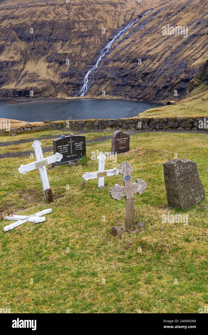 Headstones and crosses in church cemetery with waterfall at Saksun ...