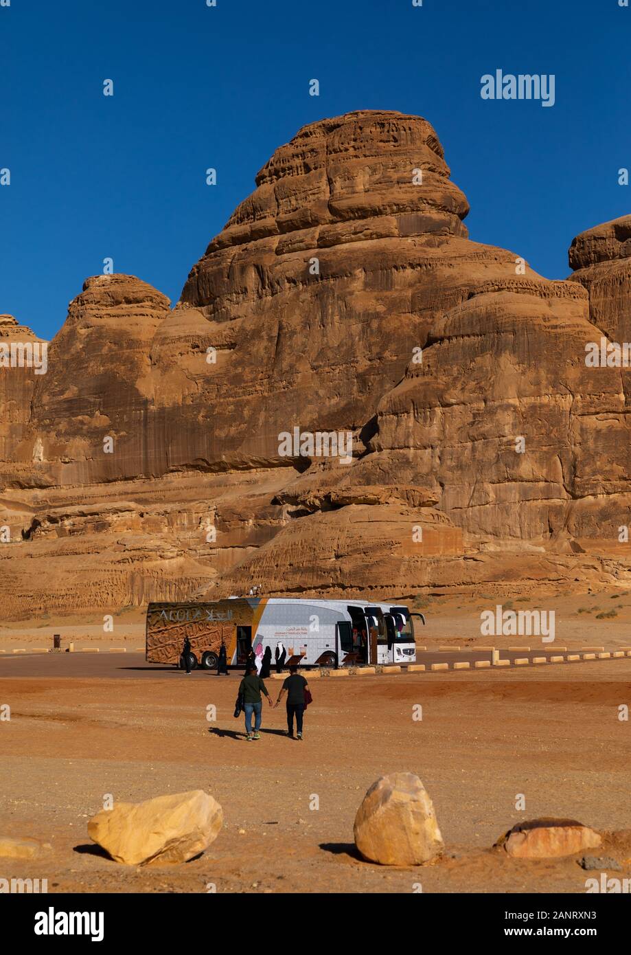 Tourists coming out of a bus during a visit in Madain Saleh ...