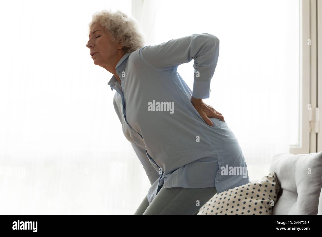 Unhappy older woman feeling pain, touching lower back Stock Photo - Alamy