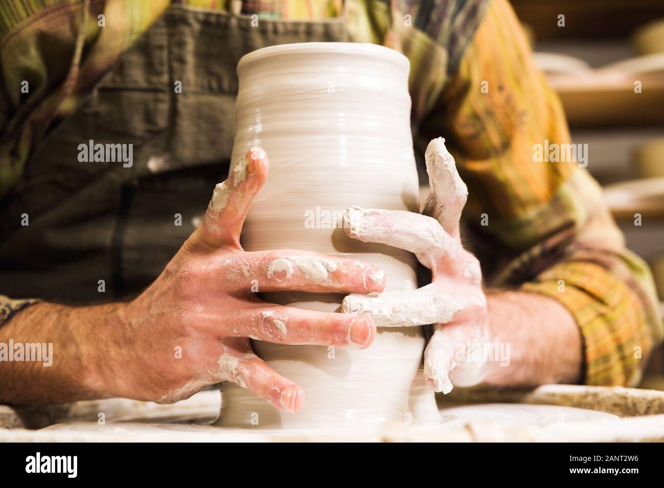 Male master potter working on potter's wheel with raw clay with hands ...