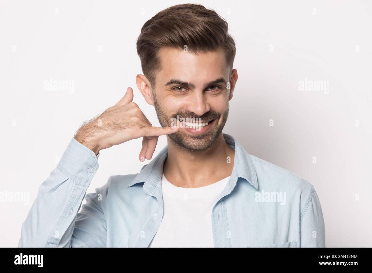 Happy smiling young guy showing call me back gesture Stock Photo - Alamy