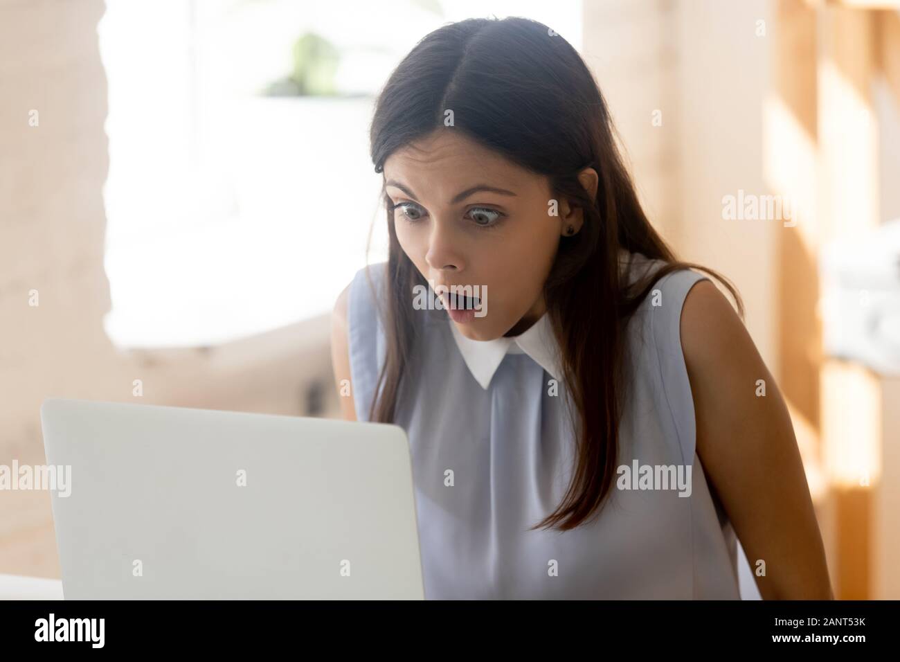 Businesswoman makes big eyes looking at computer screen feels shocked ...