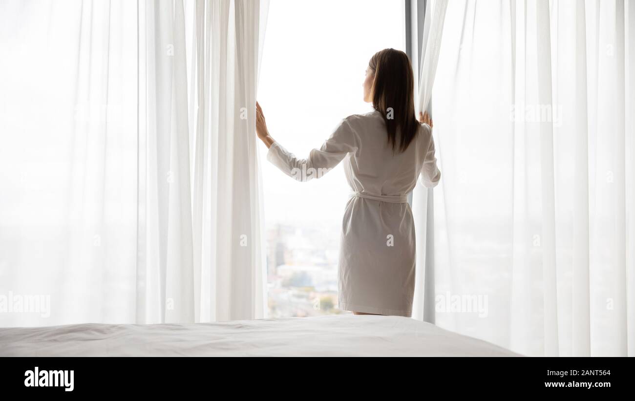 Rear view beautiful woman looking out window in modern apartment Stock ...