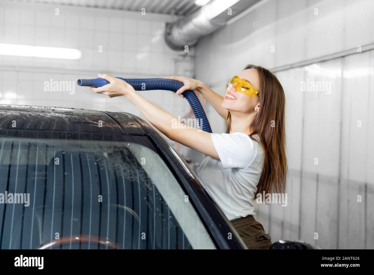 Girl worker uses turbo dryer to remove drops of water. Service car wash ...