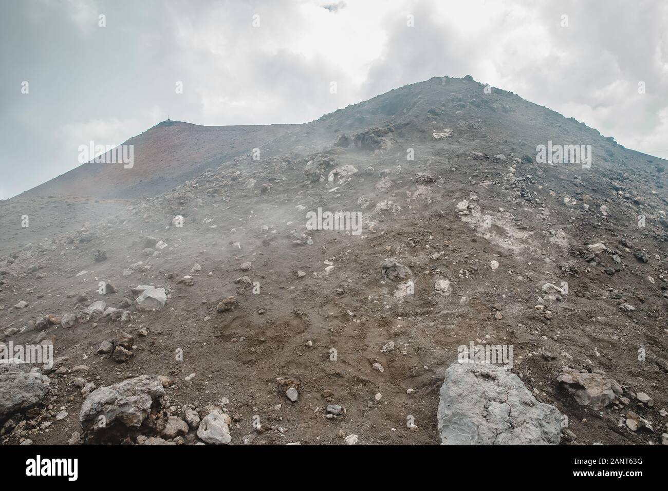 Top of crater Mount Etna volcano, frozen cold lava smokes, thick clouds ...