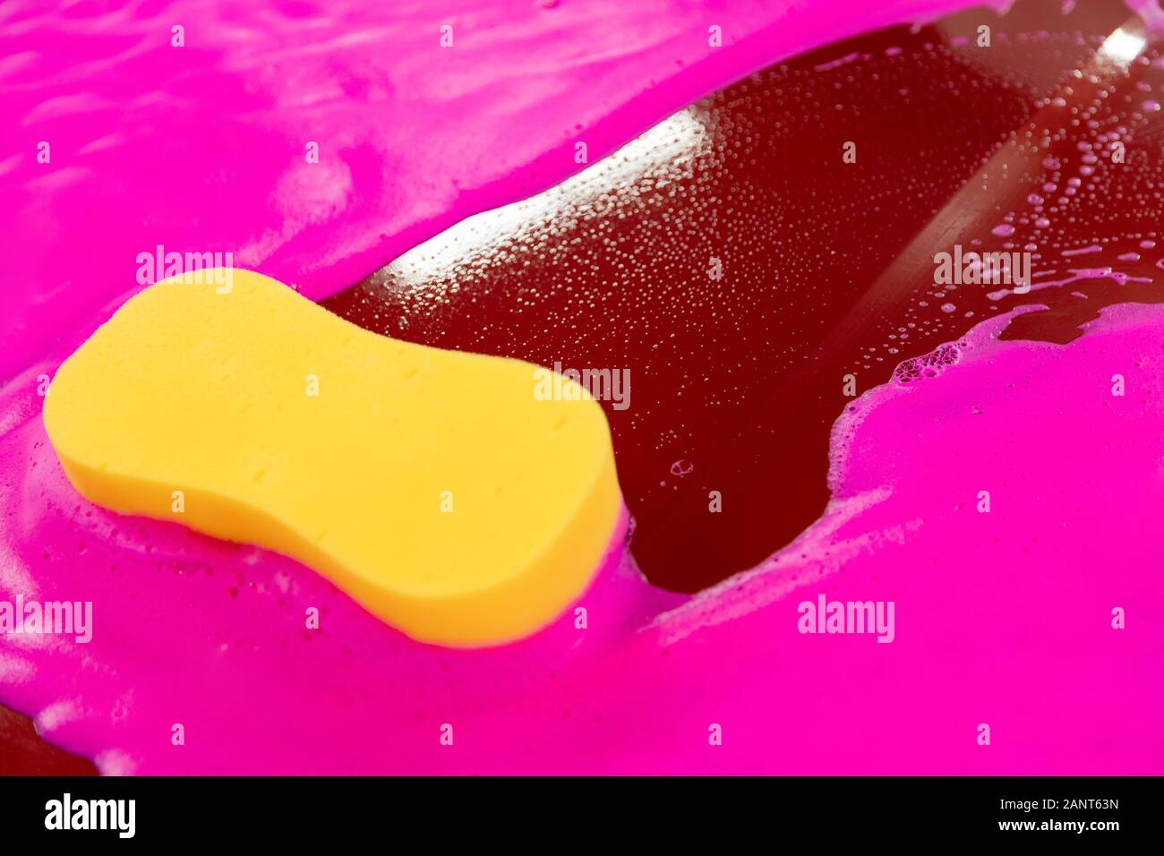 Wash car yellow sponge pink foam background Stock Photo - Alamy