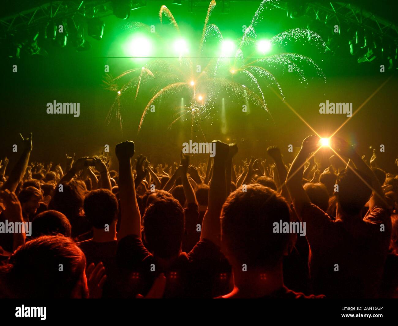 Colourful concert stage inside a venue, people silhouettes are visible ...
