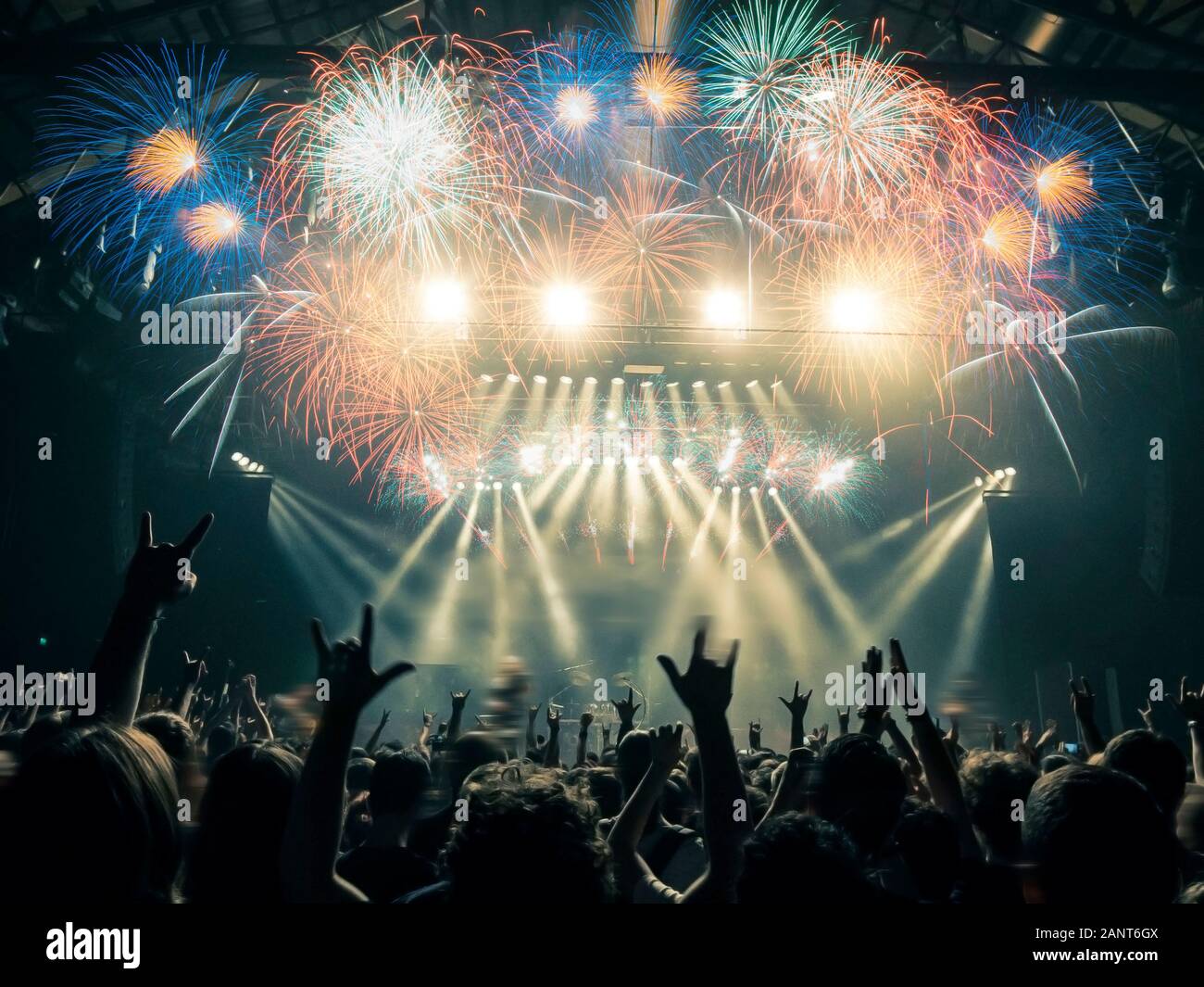 Colourful concert stage inside a venue, people silhouettes are visible ...