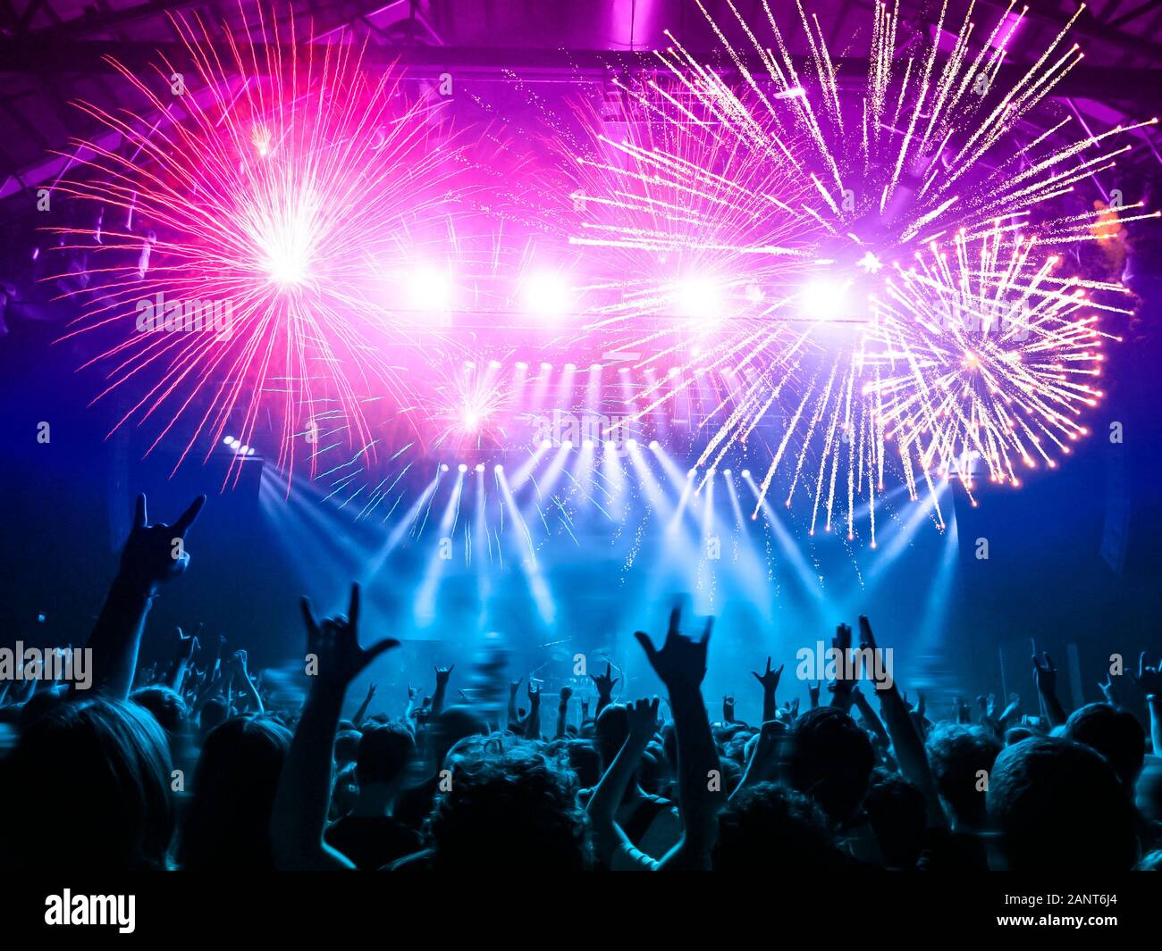 Colourful concert stage inside a venue, people silhouettes are visible ...