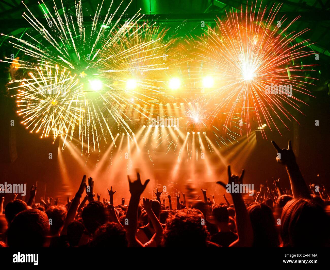 Colourful concert stage inside a venue, people silhouettes are visible ...