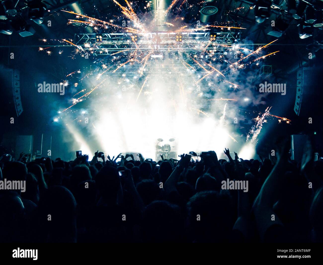 Colourful concert stage inside a venue, people silhouettes are visible ...