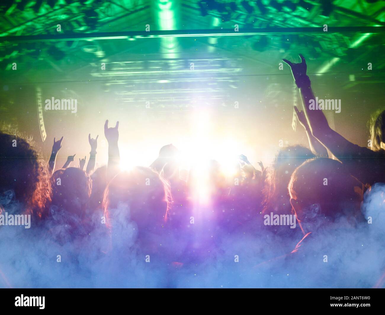 Colourful concert stage inside a venue, people silhouettes are visible ...